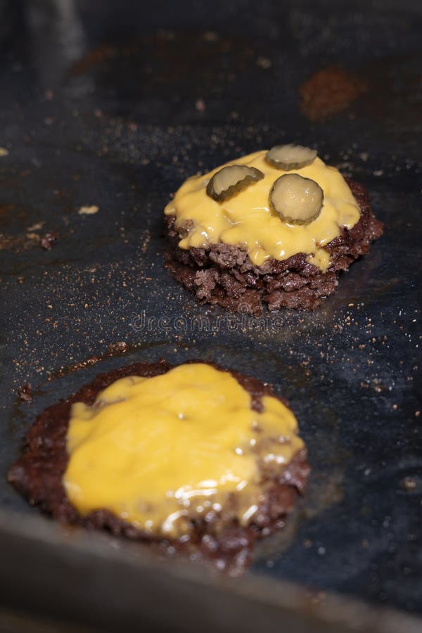 Chef Adding Cheddar Cheese and Pickles on Smash Burgers during ...