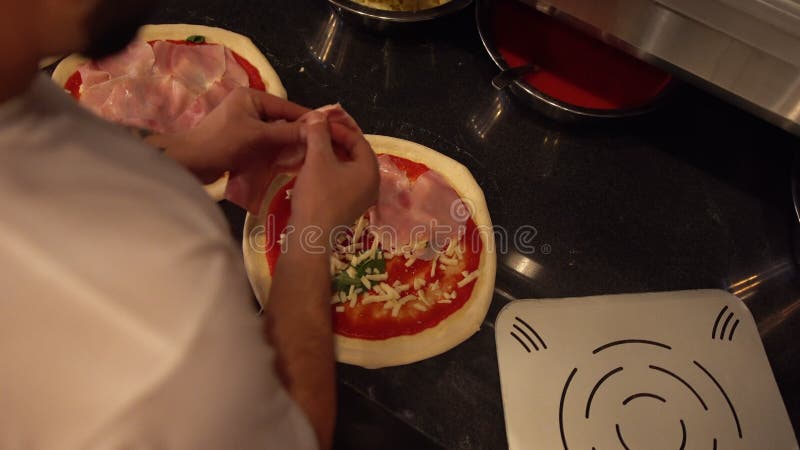 Chef Adding Sliced Ham Pieces on Pizzas in Restaurant Kitchen. Overhead ...
