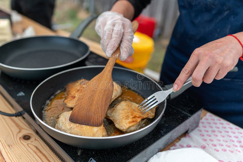 A Chef is Cooking Fish in a Pan, Using a Spatula and a Fork To Move the ...