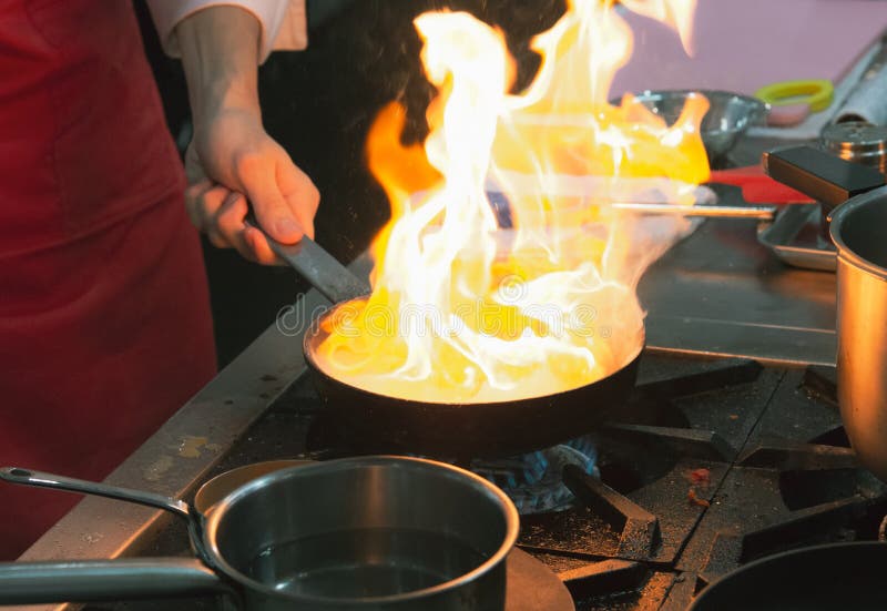 Chef Cooking with Flame in a Frying Pan on a Kitchen Stove Stock Image ...