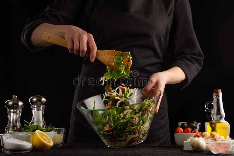 Chef Cooks a Salad, Mixed on a Black Background. Cooking and Home ...