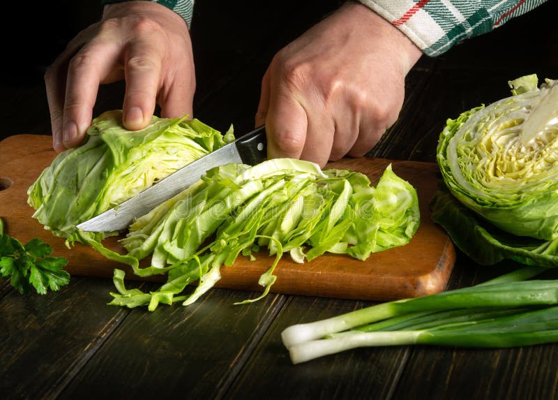 The Chef Cuts Fresh Green Cabbage on a Cutting Board with a Knife ...