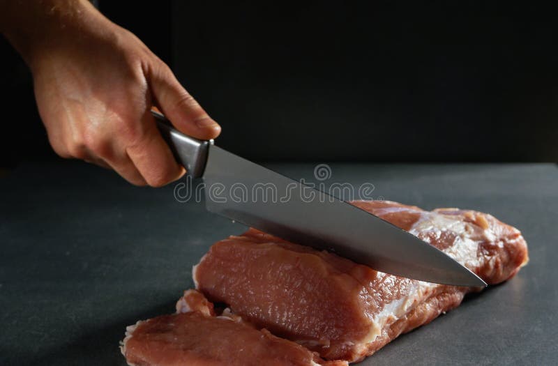 The Chef is Cutting Fresh Raw Meat into Steaks. Close-up on a Gray ...