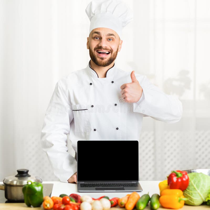 Chef Guy Holding Laptop Gesturing Thumbs-Up Standing in Kitchen Stock ...