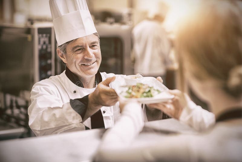 Chef Handing Dinner Dish To Waitress at Order Station Stock Photo ...