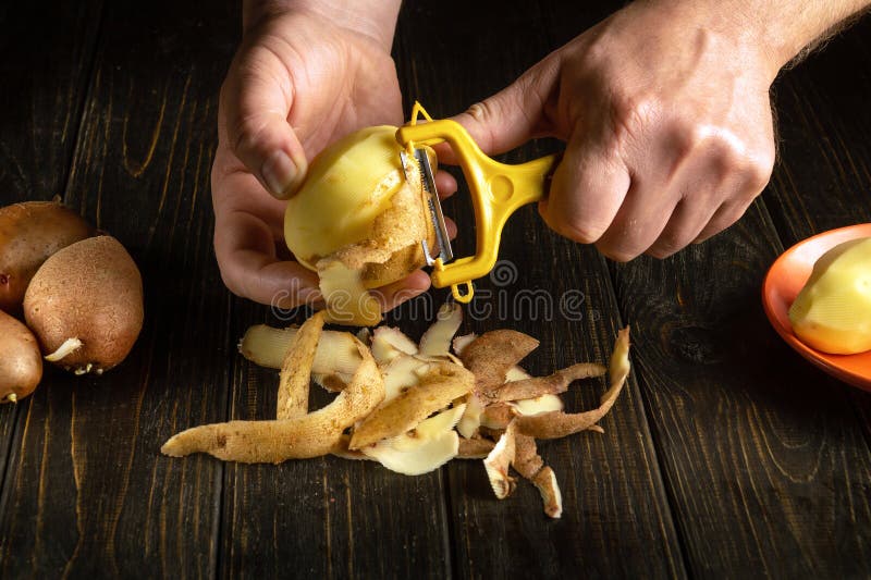 The Chef Hands Use a Special Tool To Peel Raw Potatoes Over the Kitchen ...