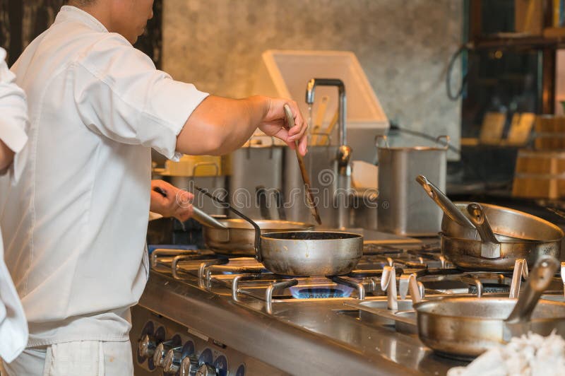 De Chef-kok In De Keuken Van Het Restaurant Op Het Fornuis Met Een Pan ...