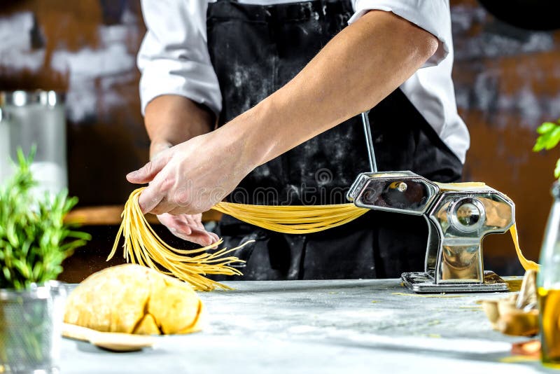 Chef Making Spaghetti Noodles with Pasta Machine on Kitchen Table with ...