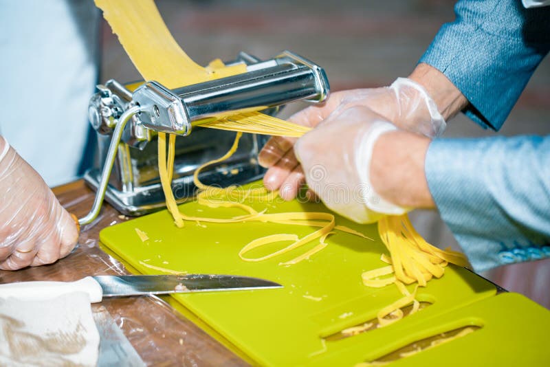 Chef Making Spaghetti Noodles with Pasta Machine on Kitchen Table Stock ...