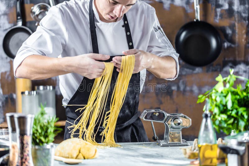 Chef Making Spaghetti Noodles with Pasta Machine on Kitchen Table with ...
