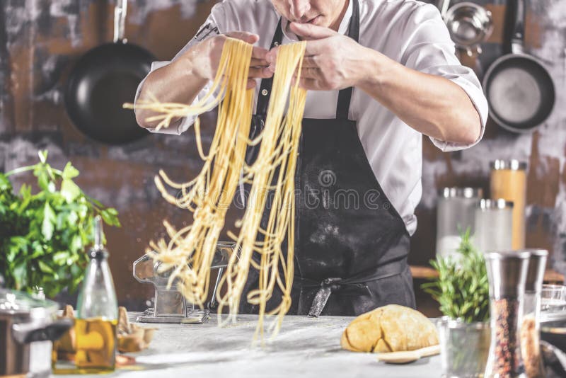 Chef Making Spaghetti Noodles with Pasta Machine on Kitchen Table with ...