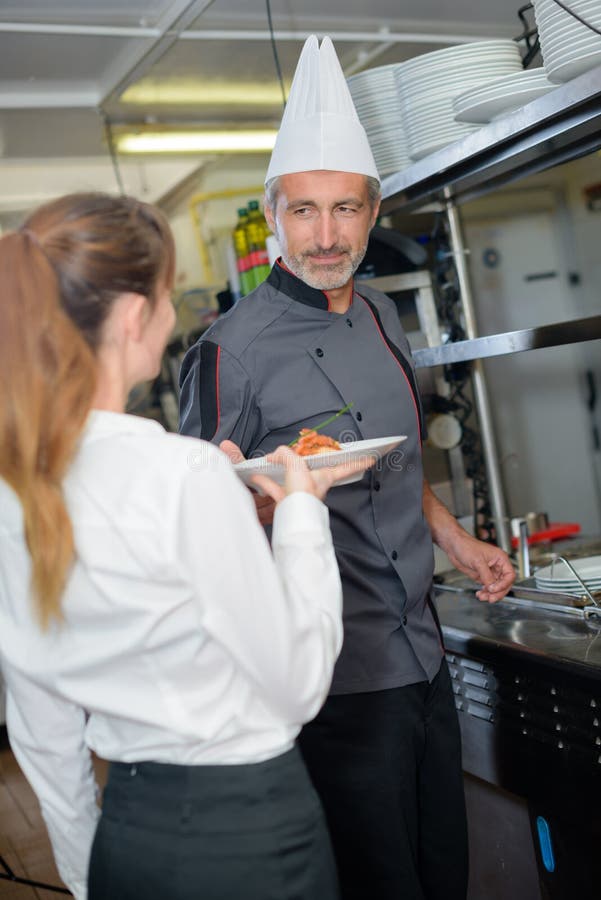 Chef Passes Plate Food To Waitress in Kitchen Stock Image - Image of ...