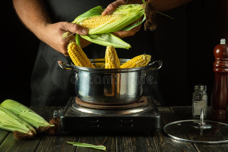 A Chef Peeling the Skin Off a Corn Cob at a Kitchen Counter before ...