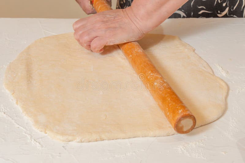 Chef Rolls Out Fresh Dough with a Wooden Rolling Pin on a White Wooden ...