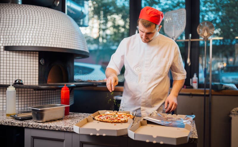 The Chef Sprinkles the Pizza in a Box with Spices. Catering Kitchen ...