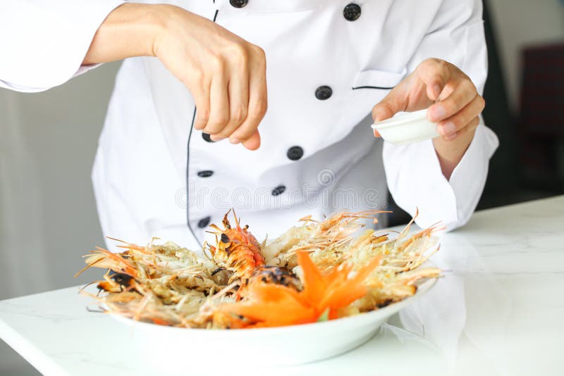 Chef Sprinkling Salt All Over Grilled Prawns in the Kitchen. Stock ...