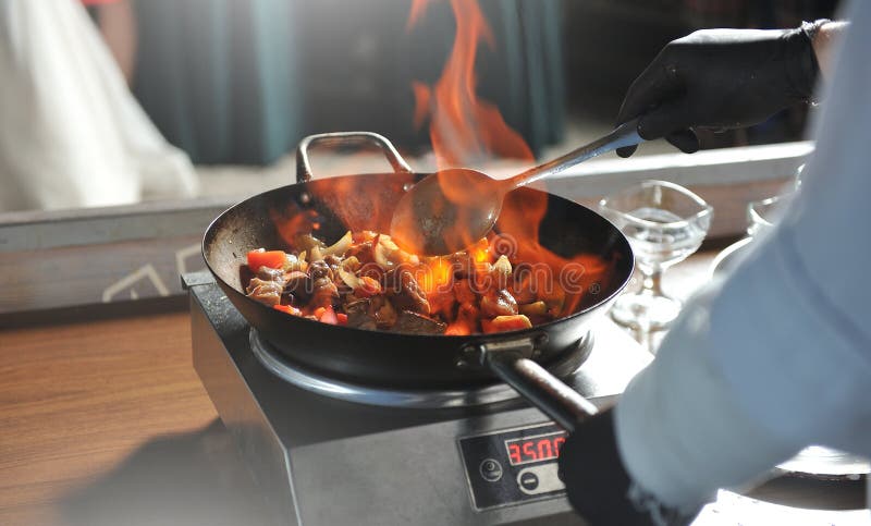A Chef Stirs Food in a Skillet with Fire on a Cooking Show Stock Photo ...