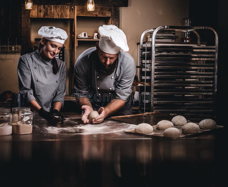 Chef Teaching His Assistant To Bake the Bread in a Bakery. Stock Photo ...