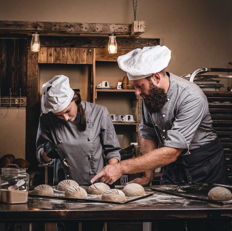 Chef Teaching His Assistant To Bake the Bread in a Bakery. Stock Photo ...