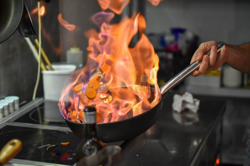 Chef Tossing Vegetables Flambe in a Pan Over the Burner Stock Photo ...