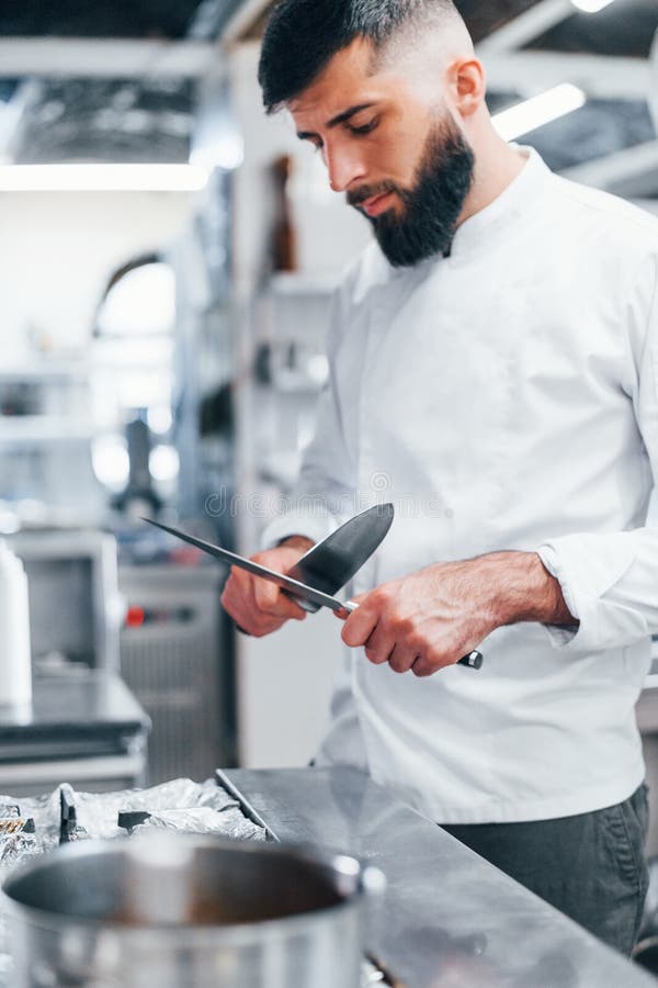 Chef in White Uniform Standing at Kitchen. Holding Knives in Hands ...