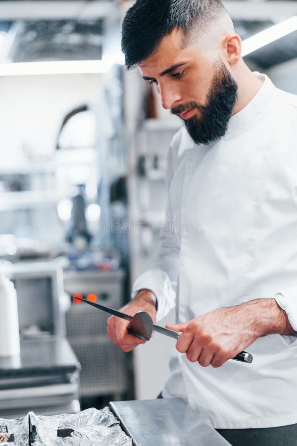 Chef in White Uniform Standing at Kitchen. Holding Knives in Hands ...