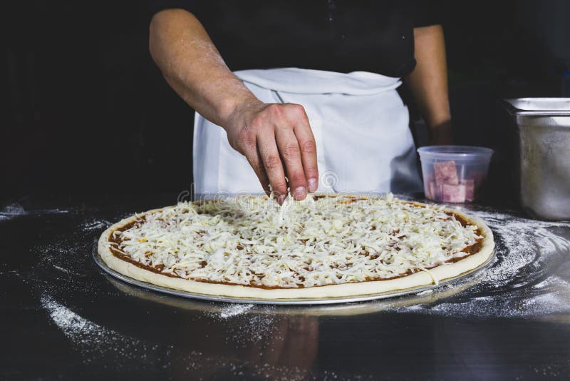 Chefs Hand Putting Cheese on the Pizza in Black Background. Stock Photo ...