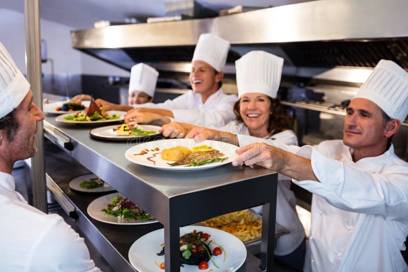 Chefs Handing Dinner Plates through Order Station Stock Image - Image ...
