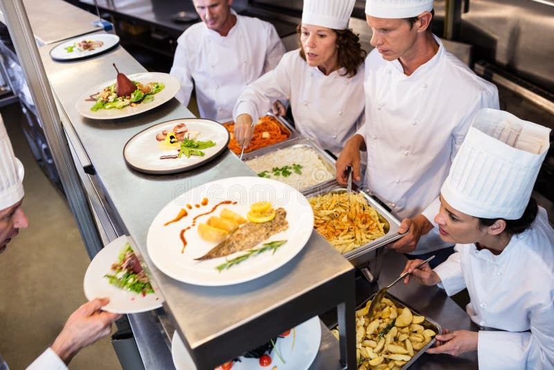 Chefs Handing Dinner Plates through Order Station Stock Photo - Image ...