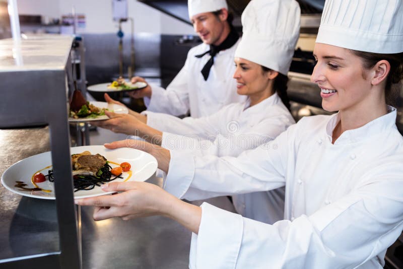 Chefs Handing Dinner Plates through Order Station Stock Photo - Image ...