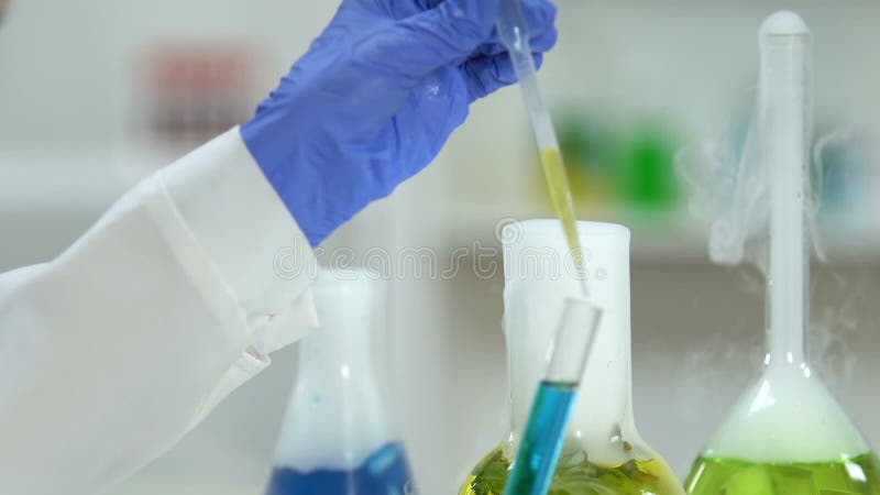 Chemist Adding Drops of Boiling Plant Extract into Test Tube with Blue ...