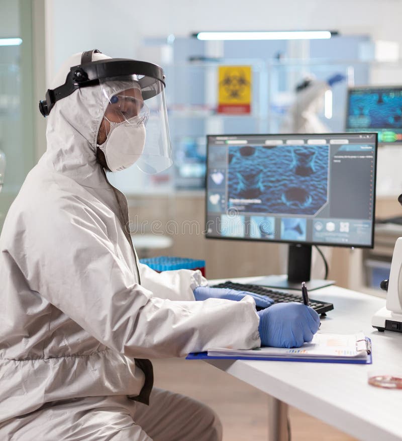 Chemist Researcher Dressed in Ppe Suit with Visor Writing on Clipboard ...