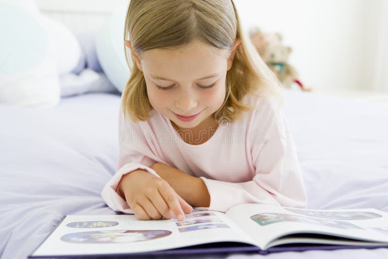 Chica Joven Que Miente En Su Cama Que Lee Un Libro Foto De Archivo