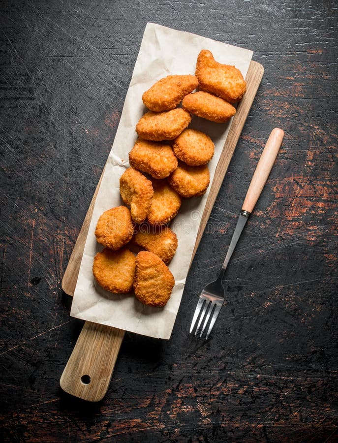 Chicken Nuggets on Cutting Board with Paper and Fork Stock Image ...