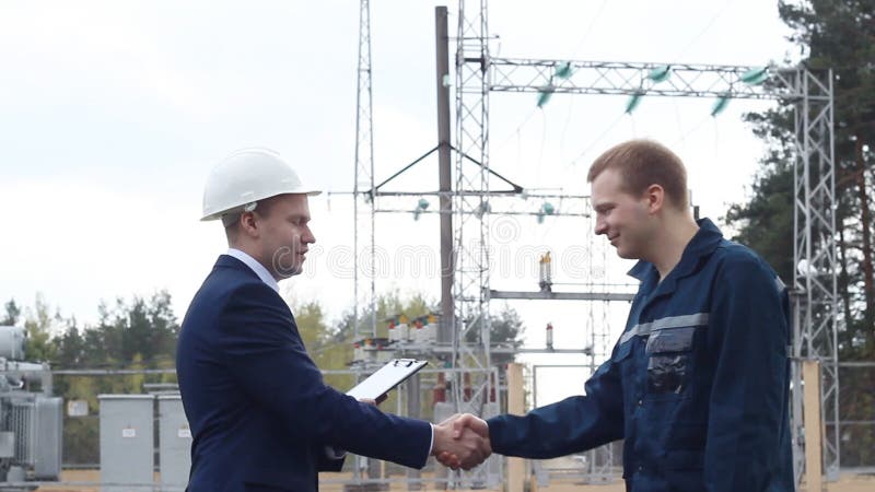 Handshake of Two Electrical Engineers Against the Backdrop of High ...