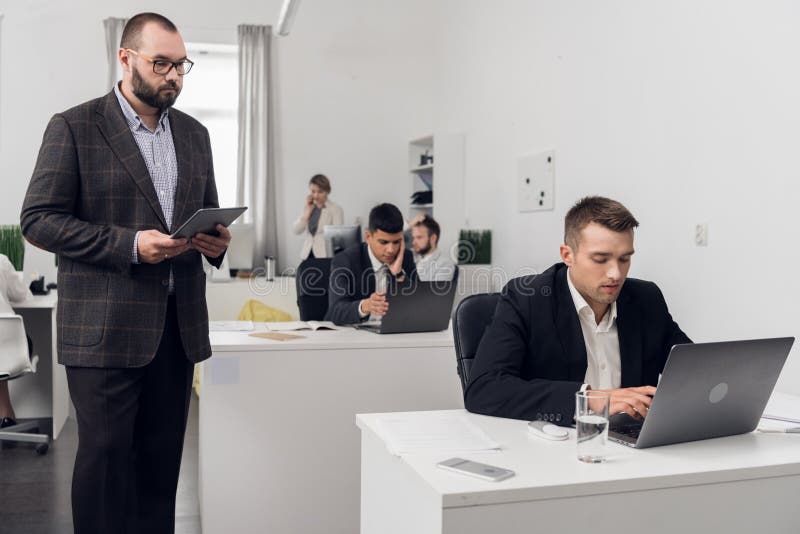 Chief Stands Over the Man Sitting at a Table and Working on a Laptop ...