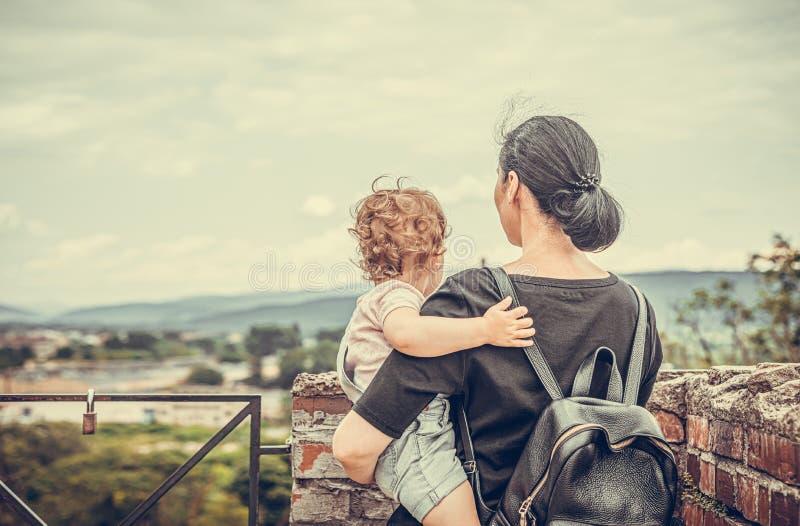 Child In The Arms Of The Mother Looking Into The Distance. Back View ...