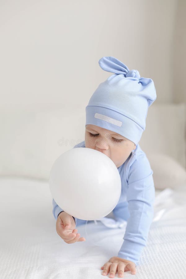 A Child on a Bed in a Blue Suit with a Hat Stock Photo - Image of ...