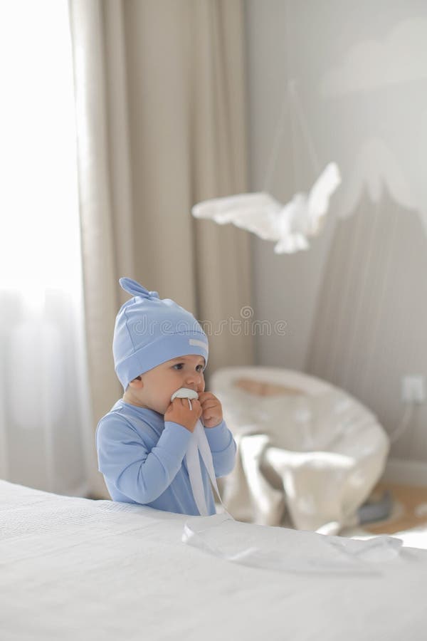 A Child on a Bed in a Blue Suit with a Hat Stock Photo - Image of ...
