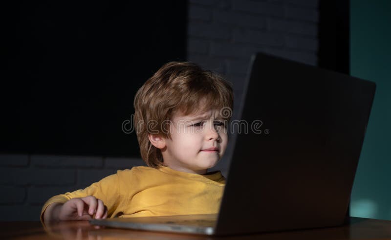 Child is Bored at the Computer at Night in the Dark. Seated Child Using ...