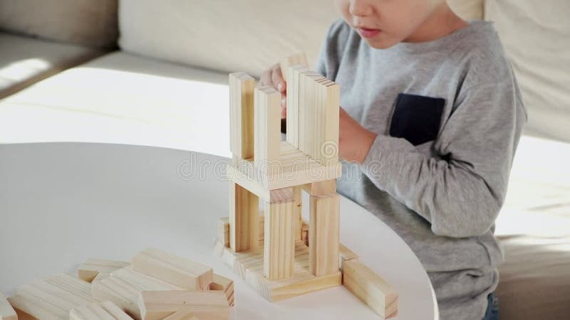 Child Build a Tower from Wooden Blocks Sitting on the Sofa at Home ...