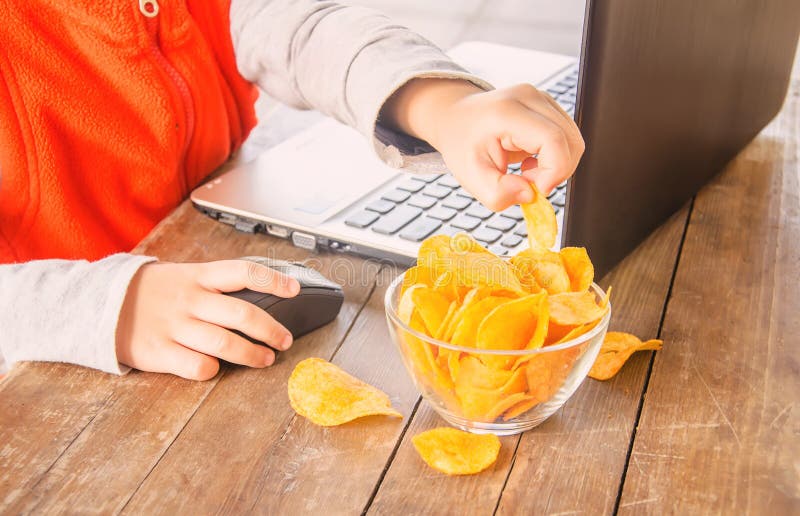 Child with Chips Behind a Computer. Selective Focus Stock Photo - Image ...