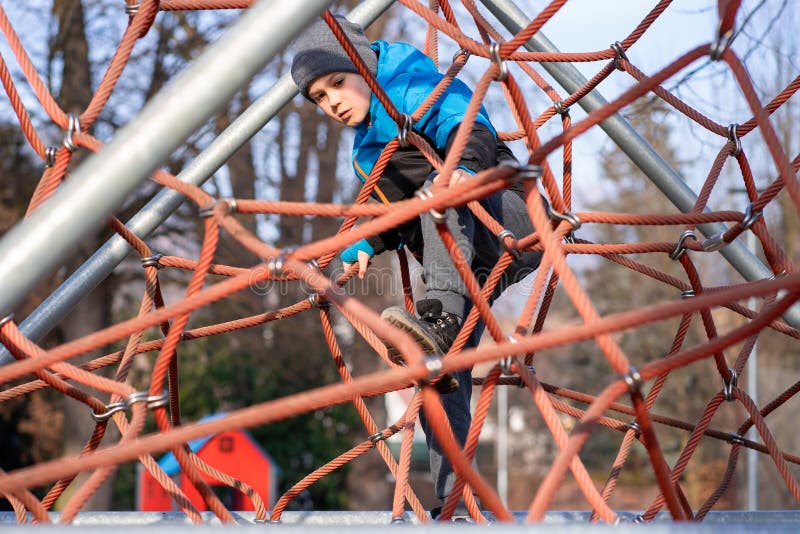 A Child Climbs Up an Alpine Grid in a Park on a Playground on Spring ...