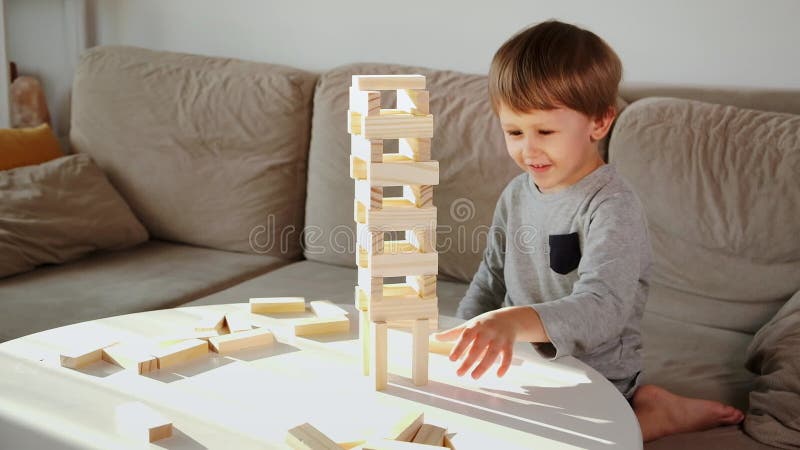 Child Crash a Tower from Wooden Blocks Sitting on the Sofa at Home ...