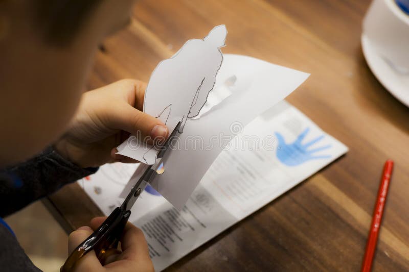 A Child Cuts Paper with Scissors, Carves Figures of Knights while ...