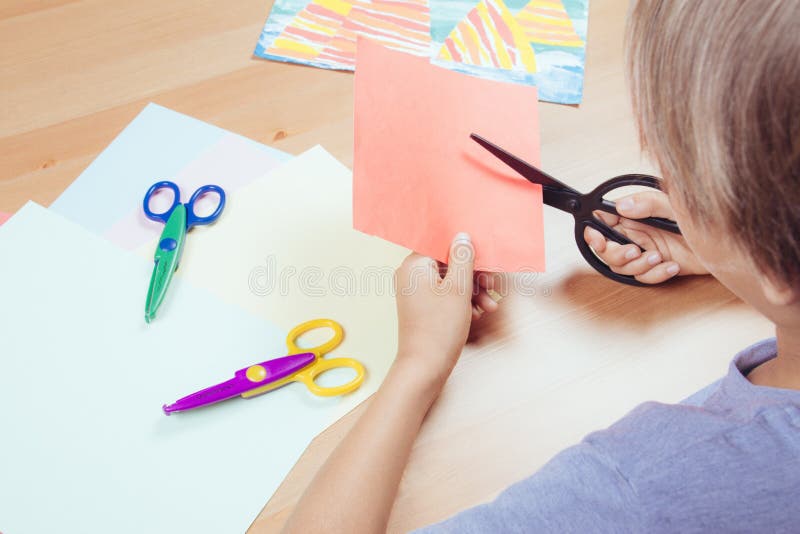 Child Cutting Colored Paper with Scissors at the Table Stock Photo ...