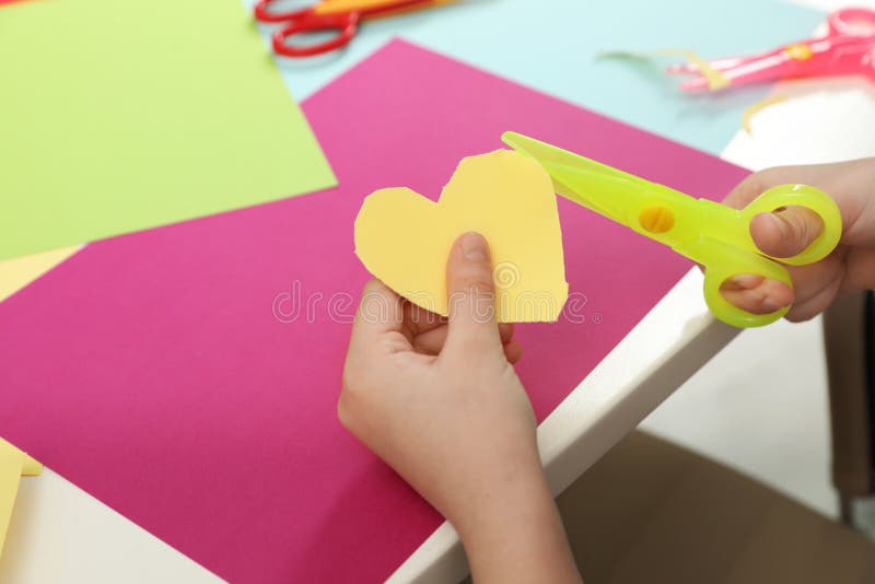 Child Cutting Out Paper Heart with Plastic Scissors at Table, Closeup ...
