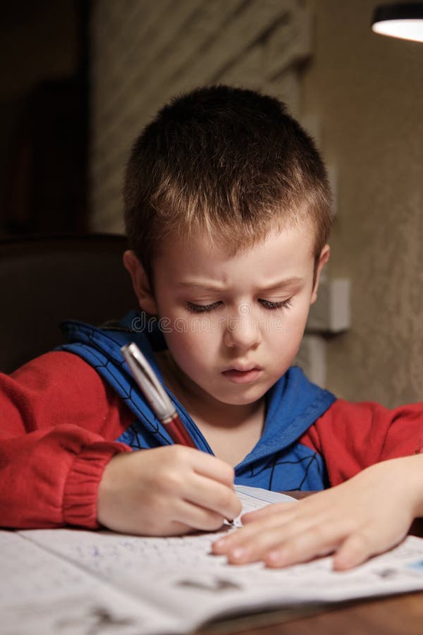 Child is Doing Homework in the Light of the Lamp in the Evening. a Boy ...