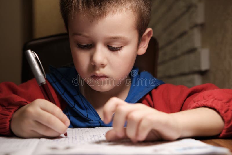 Child is Doing Homework in the Light of the Lamp in the Evening. a Boy ...