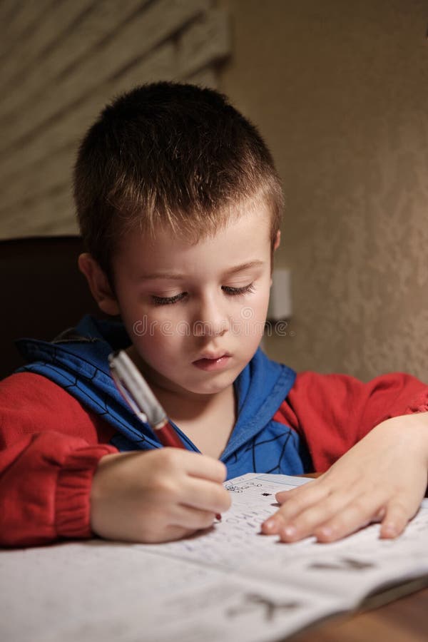 Child is Doing Homework in the Light of the Lamp in the Evening. a Boy ...